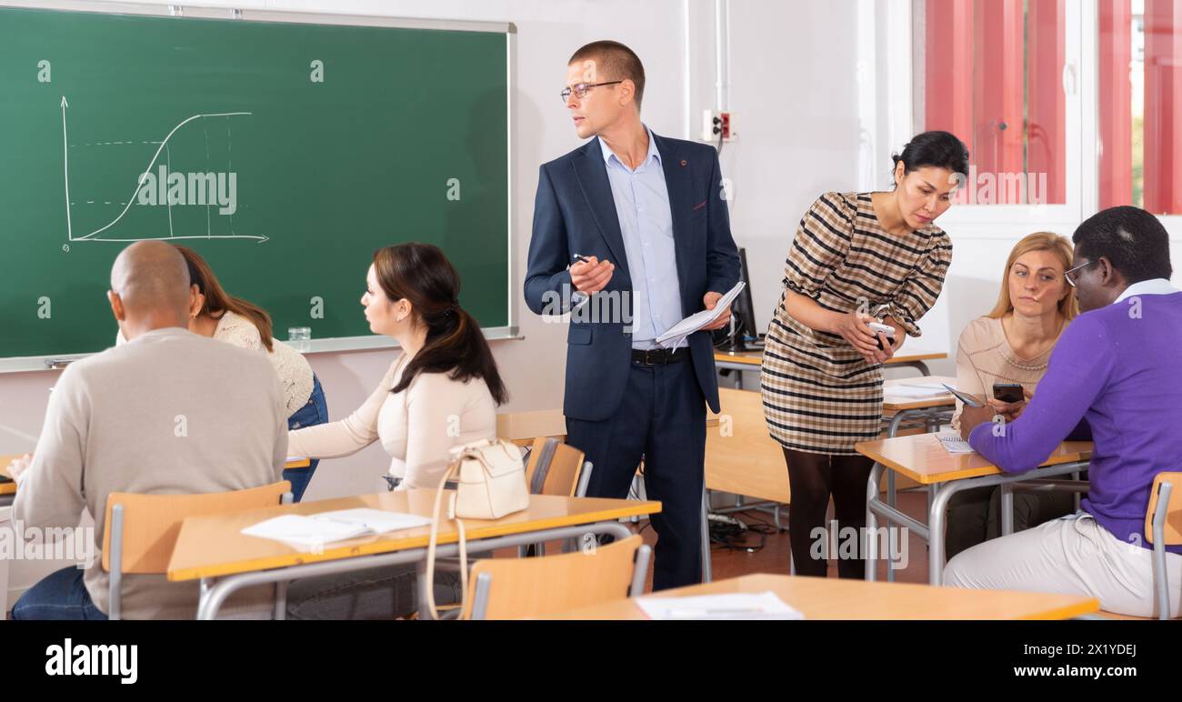 Teacher supervising work of students in groups in classroom Stock Photo ...