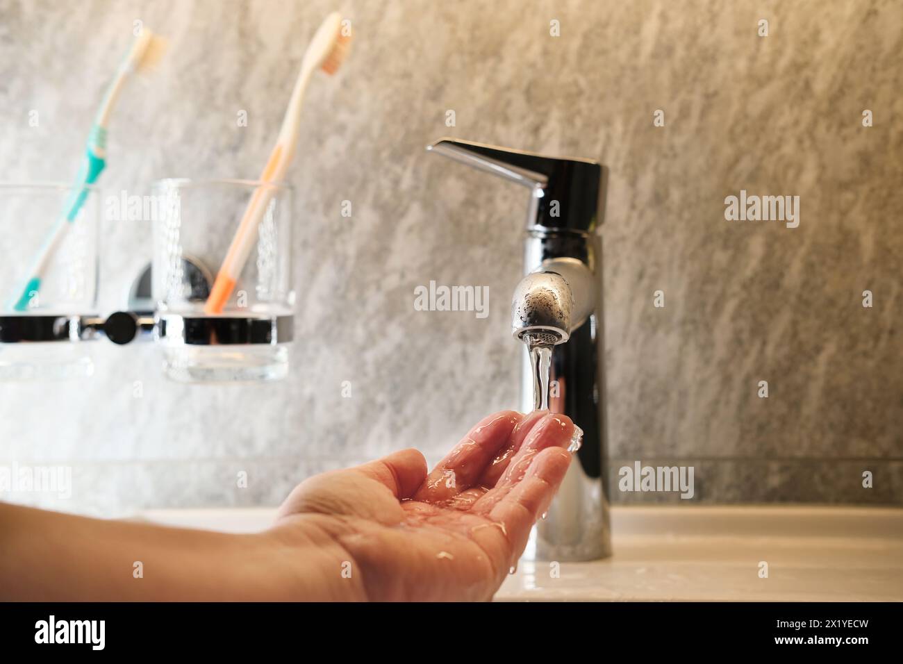 water pours a thin stream from a chrome plated faucet, the girl washes ...