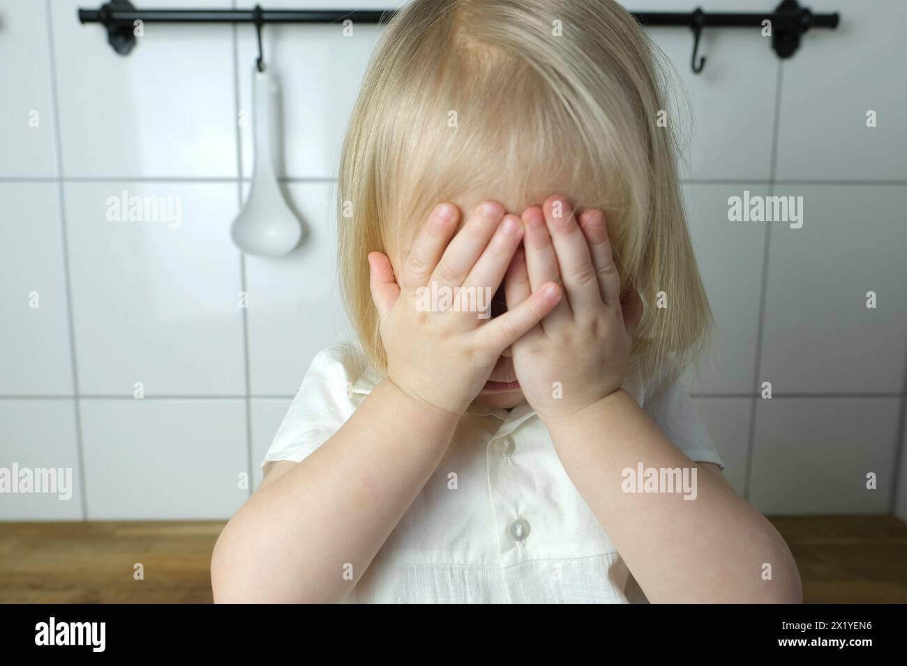 small child, baby, blonde girl covered her face with her palms from ...