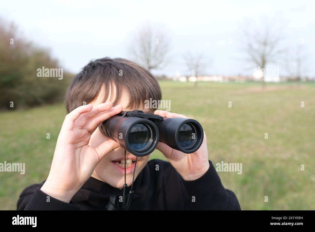 boy, guy 8-10 years old stalker looks through black binoculars in the ...