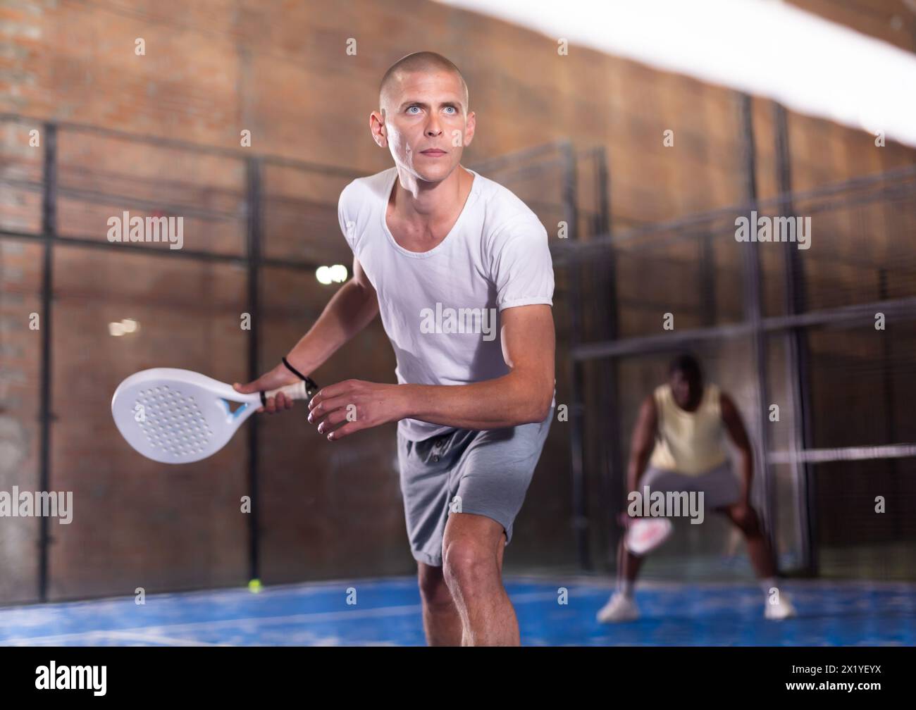 Padel player playing padel in a padel court indoor behind net Stock ...