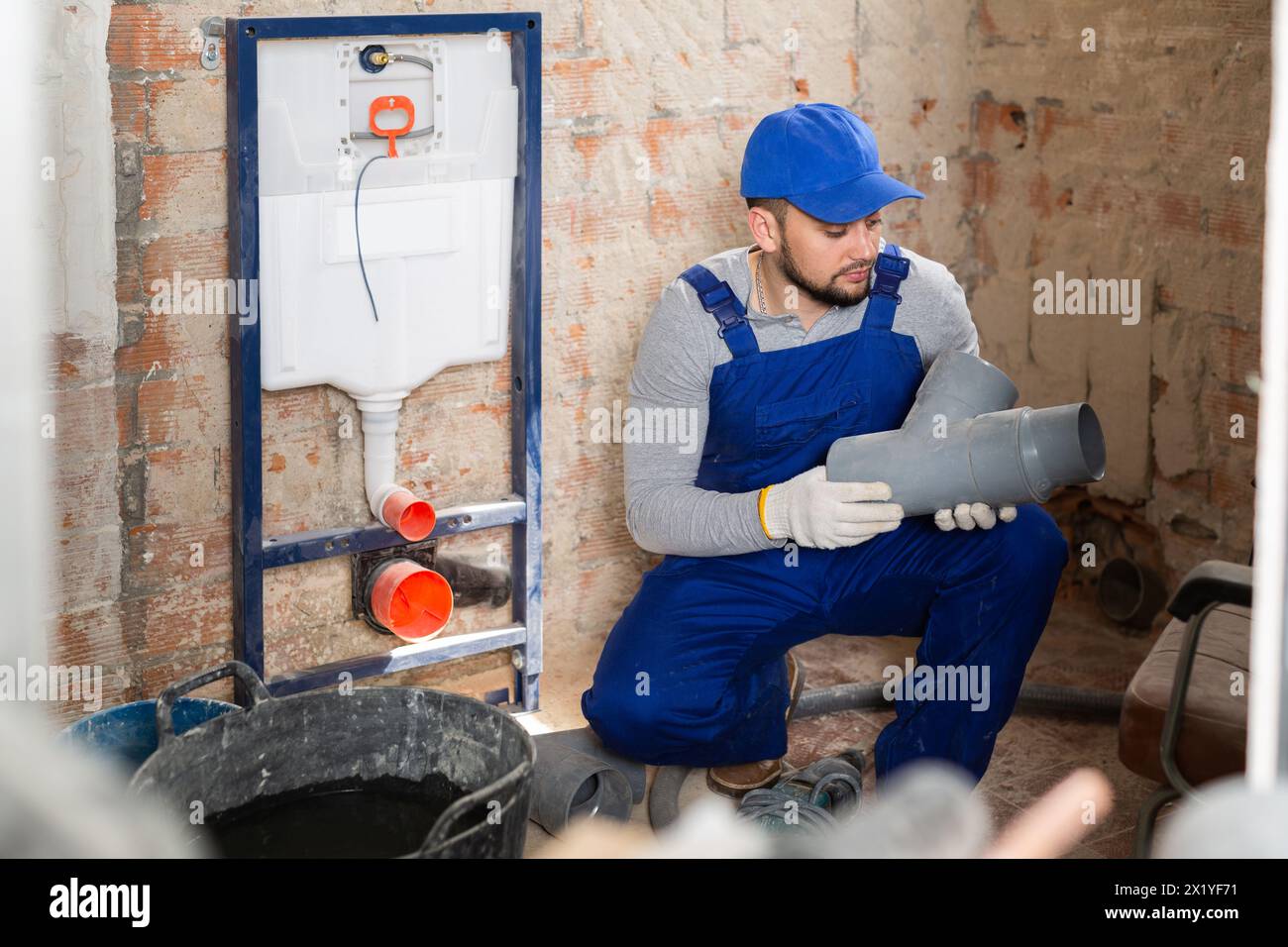 Plumber installing back to wall toilet system Stock Photo - Alamy