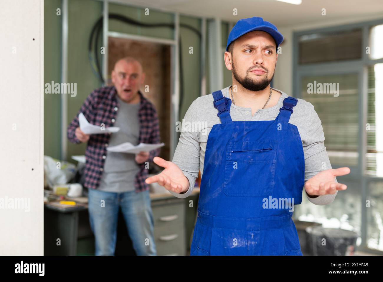 Builder making helpless gesture while his boss shouting Stock Photo - Alamy