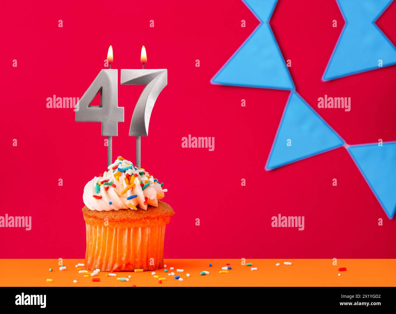 Number 47 candle with birthday cupcake on a red background with blue ...