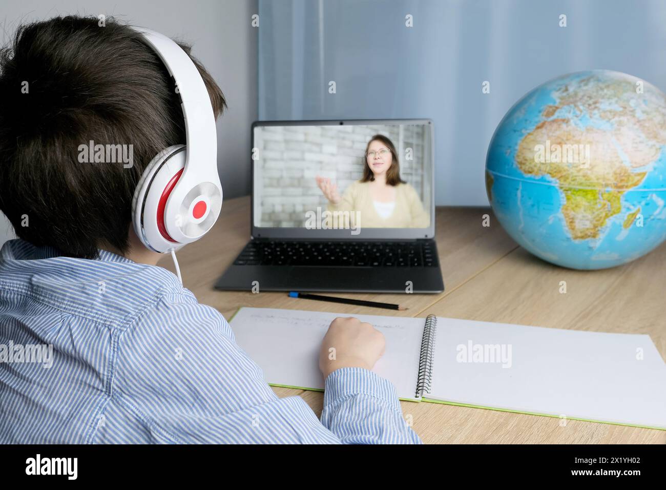 schoolchild, kid 7-8 years old doing homework in front of a laptop, the ...