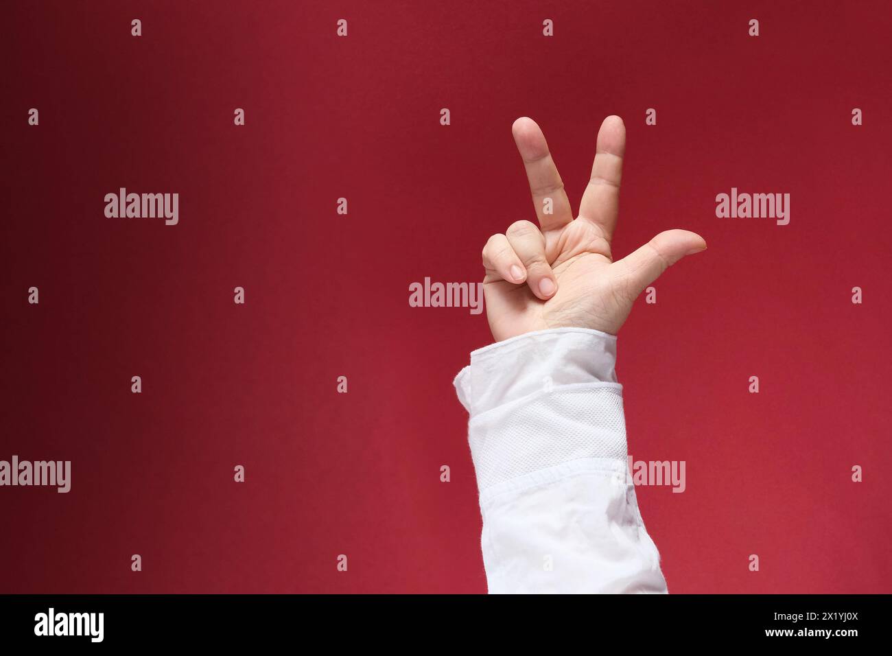female hand, finger gesture number three, red cloth background, space ...