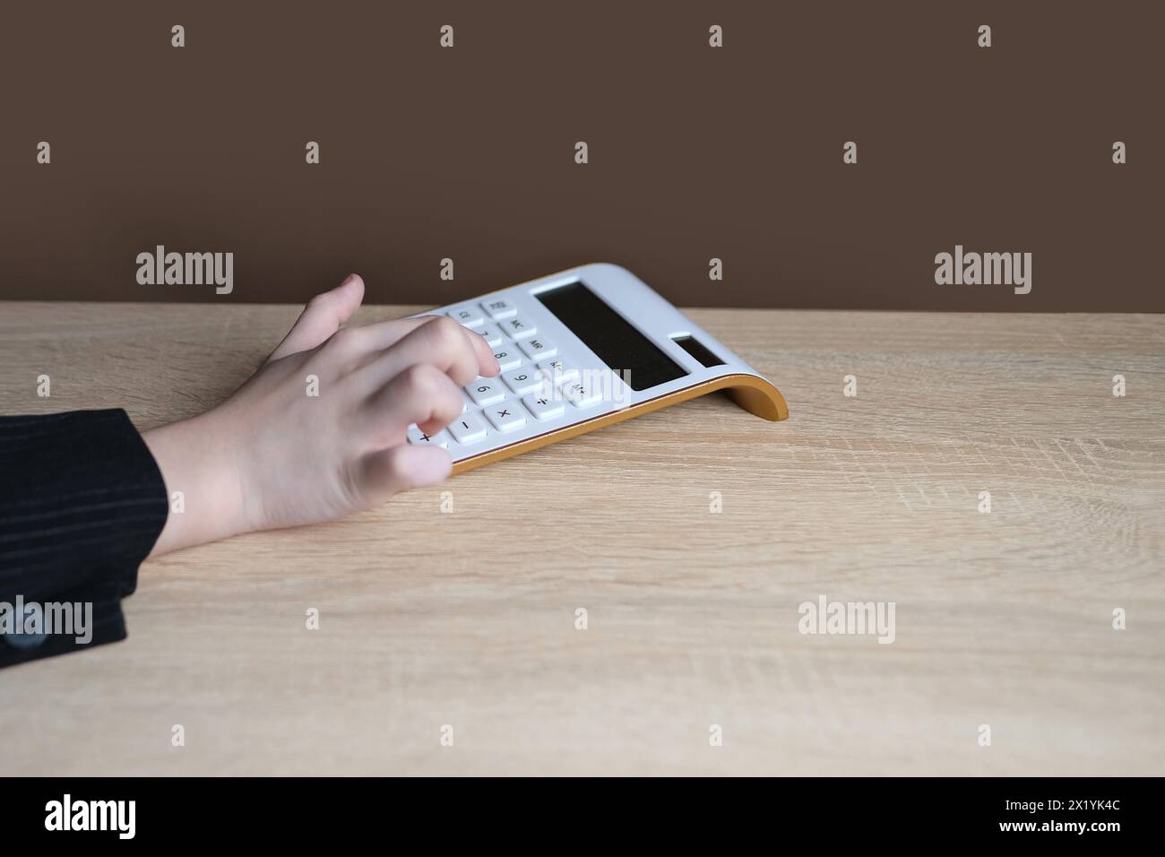 children's hand makes calculations on a white electronic calculator ...