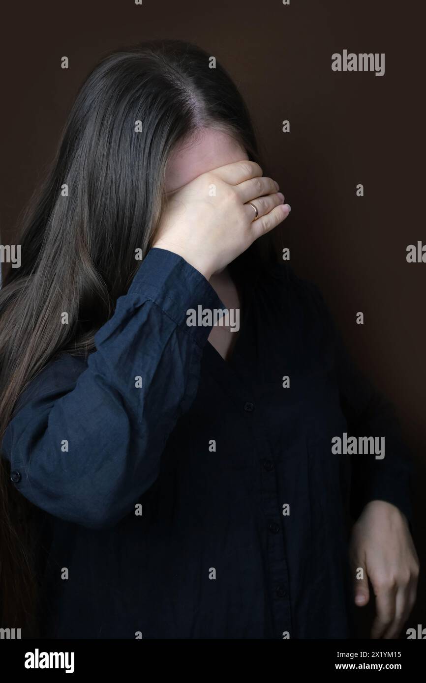 close-up face of a young woman with long brown hair under the pressure ...