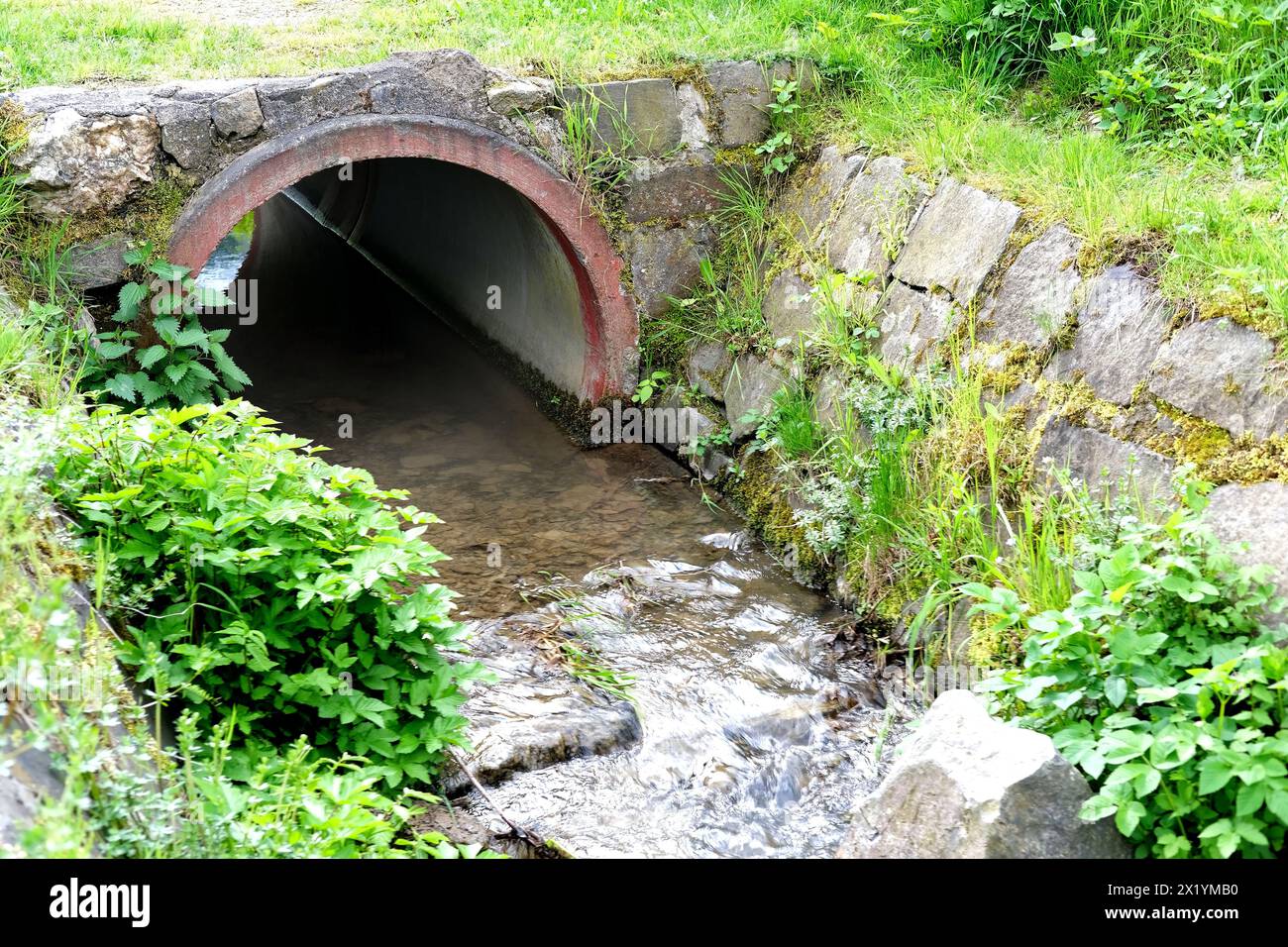 close-up concrete semicircular arch of a water drain well, a stream ...
