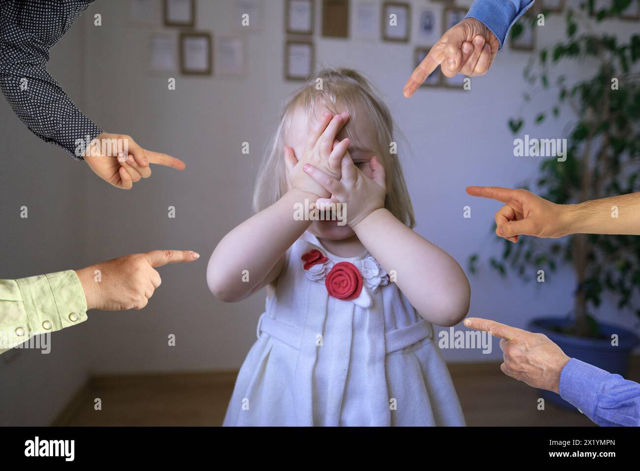 small child in a white dress, baby, a blonde girl stands, covering her ...