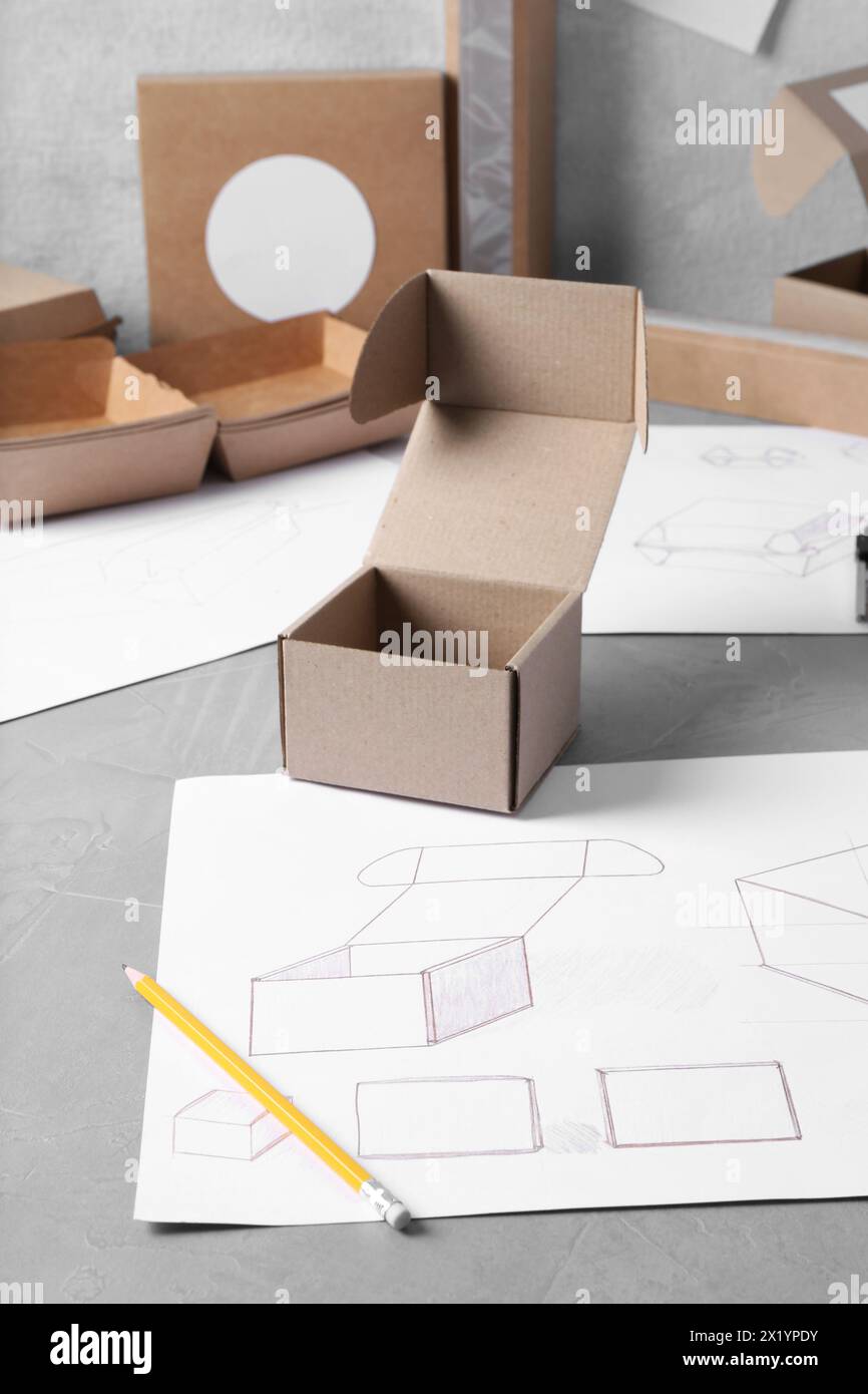 Creating packaging design. Drawings, boxes and pencil on blue textured ...