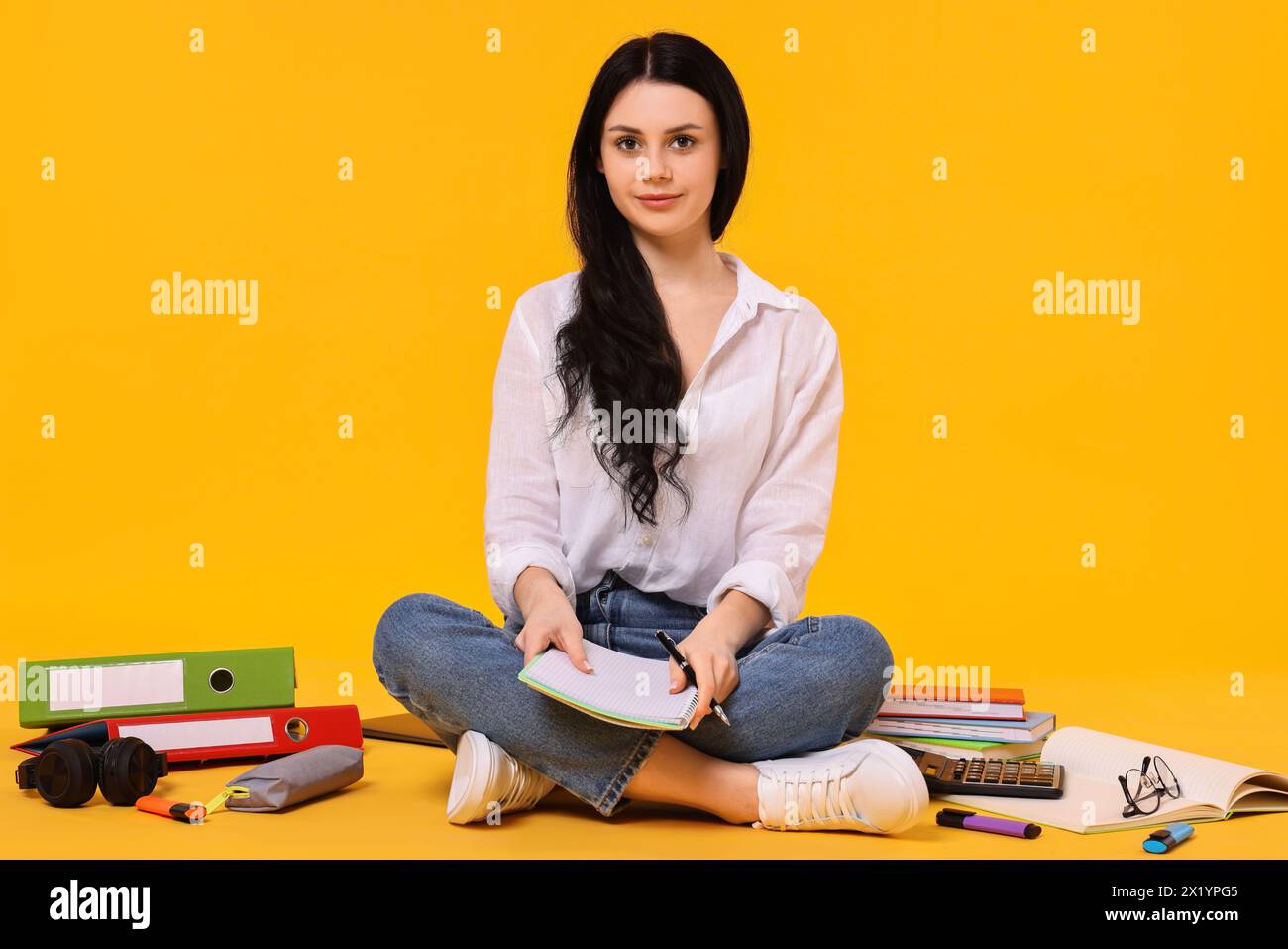 Student with notebook sitting among books and stationery on yellow ...