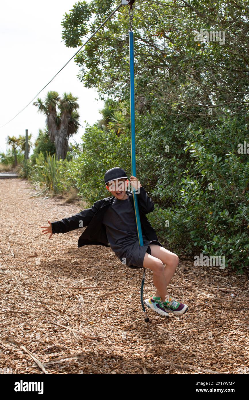 The boy is flying on a zip line in the park. A child is happily rocking ...