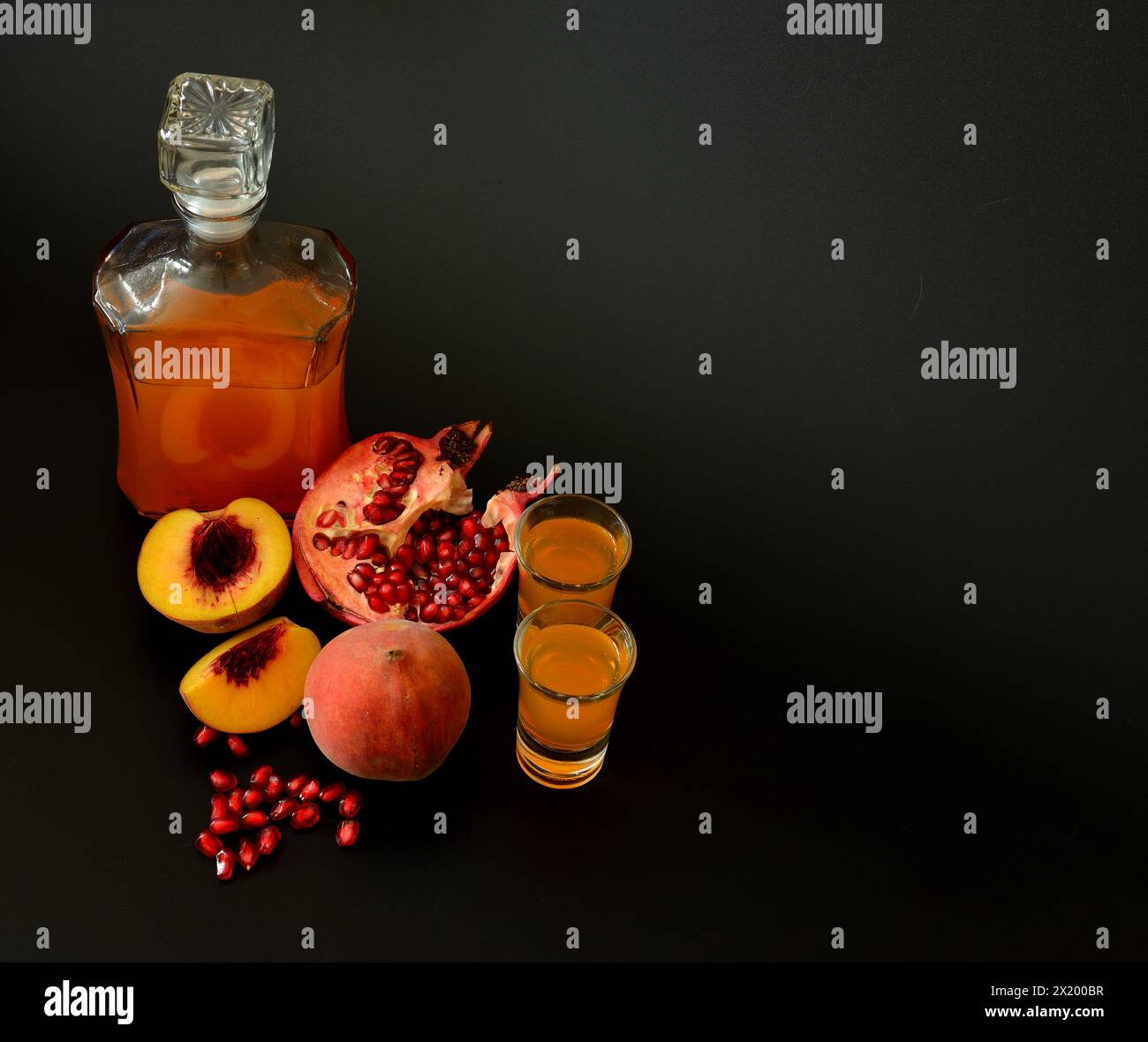Homemade fruit liqueur in a glass bottle and two glasses on a black ...