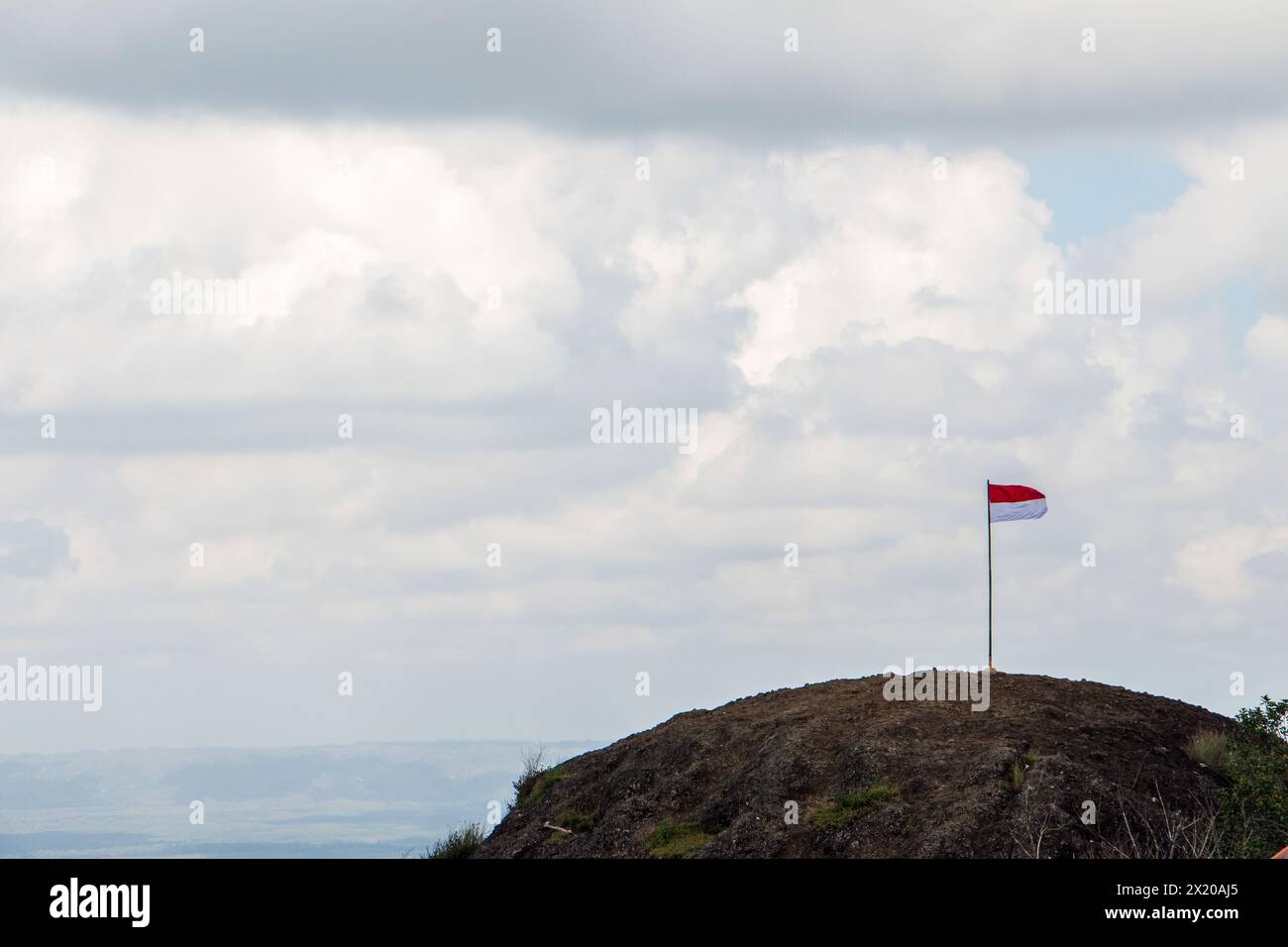 The red and white Indonesian flag flies over the peak of an ancient ...
