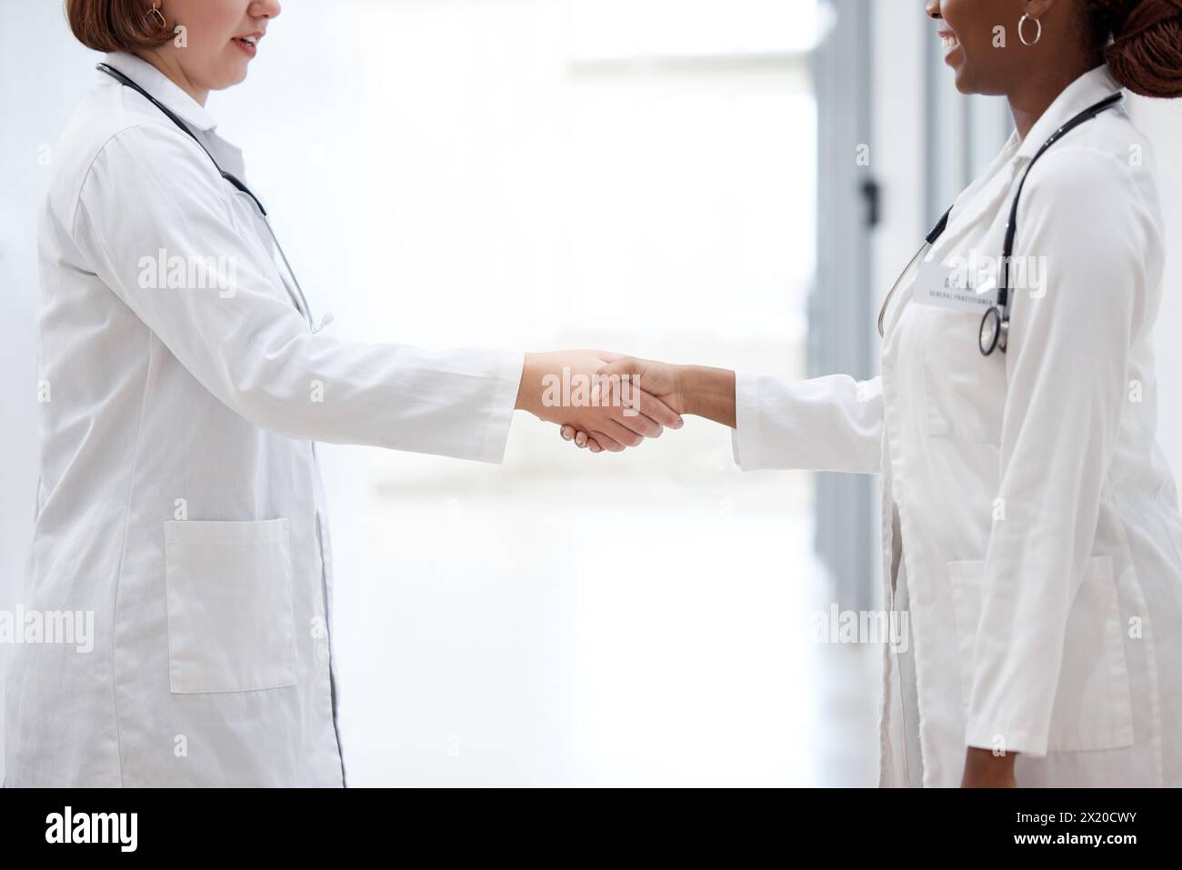 Female doctor and nurse, shaking hands for partnership, agreement and ...