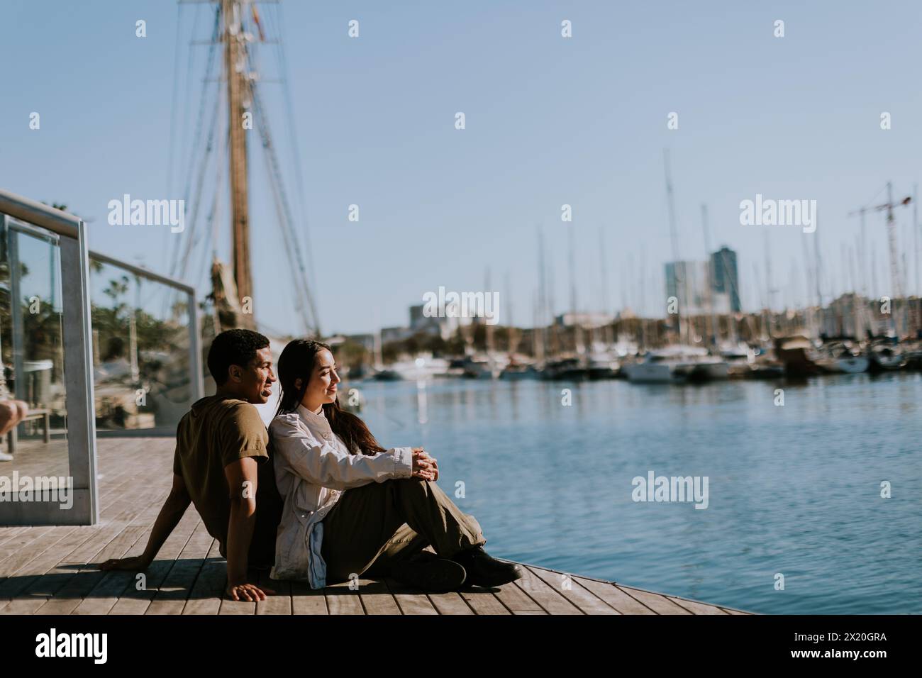 Couple sits closely on a dock, enjoying a peaceful moment overlooking ...