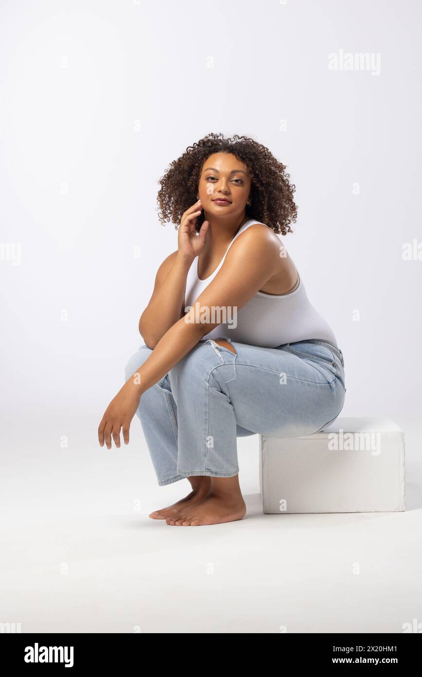 A biracial young female plus size model poses on white background, copy ...