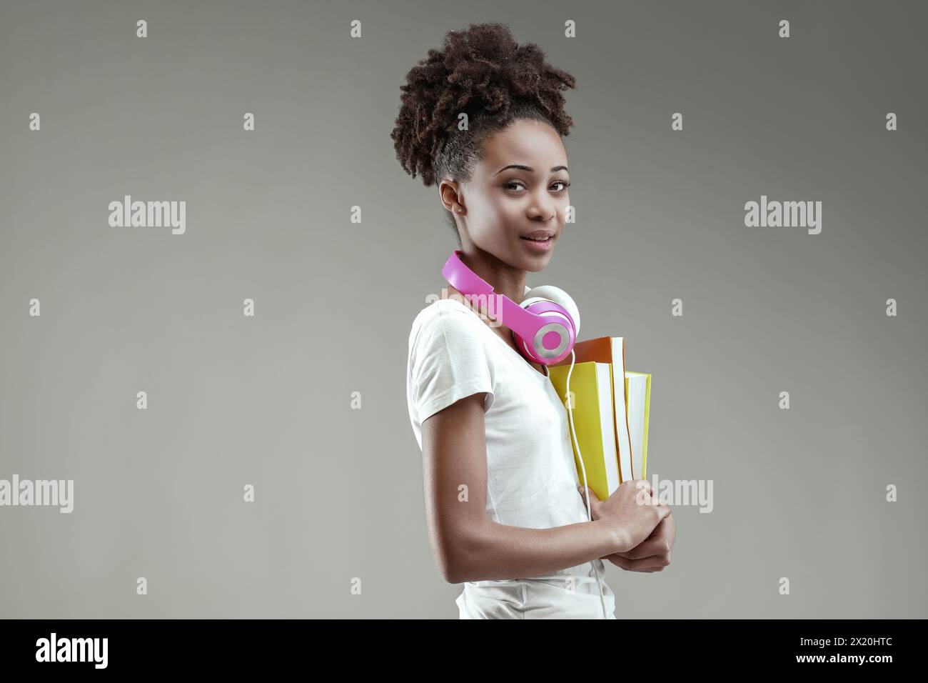 Focused young woman embraces school books and yellow binder Stock Photo ...