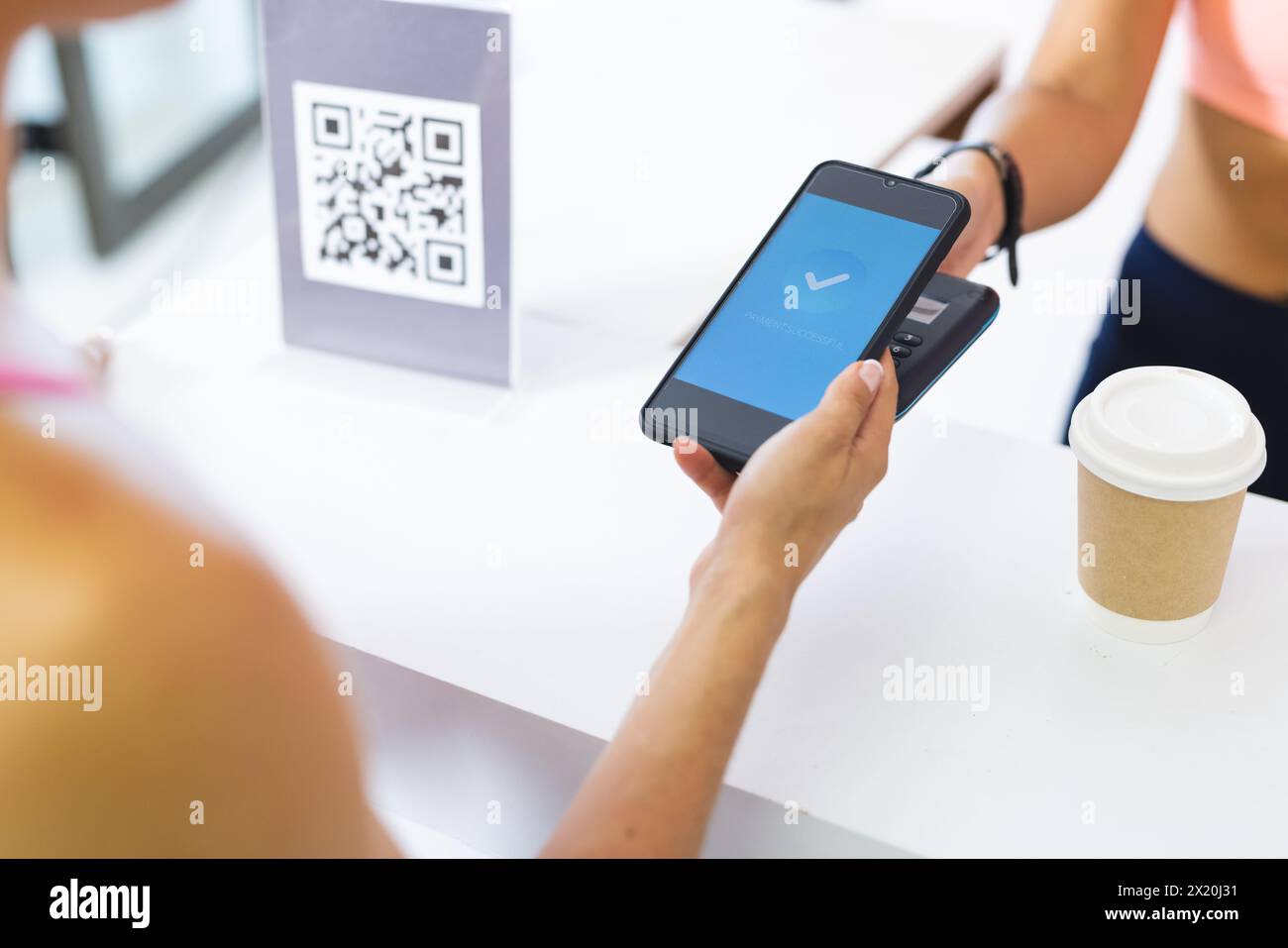 Biracial and Caucasian women in pilates studio, one scans QR code with ...