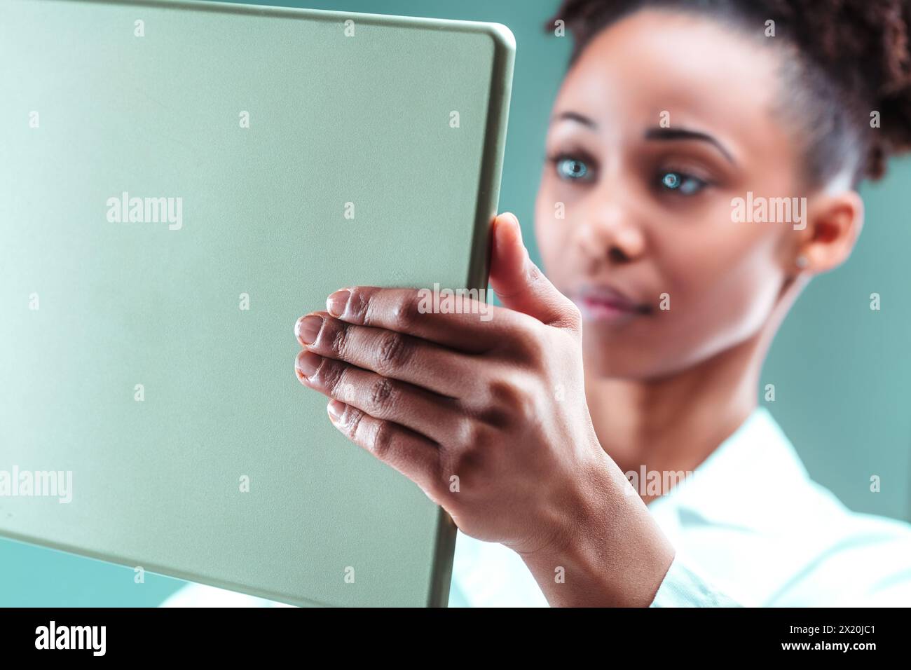 With meticulous attention, a woman in a white coat studies details on ...