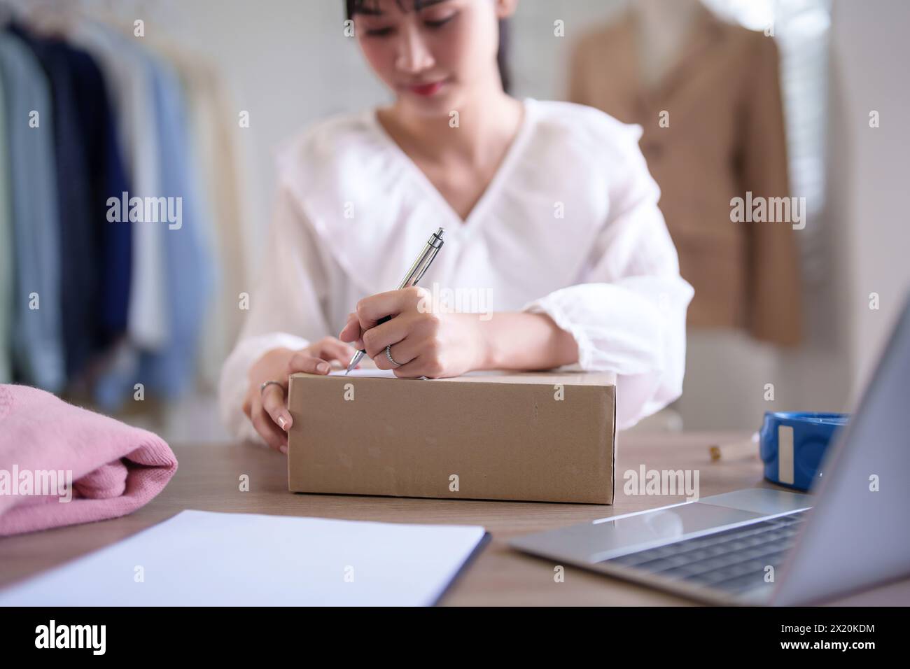 Young asian merchant women writing address data in cardboard box and ...