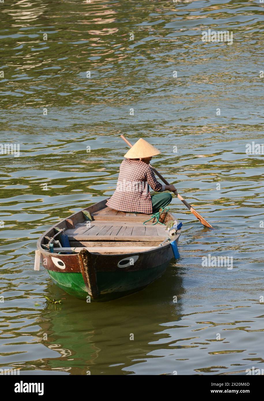 A Vietnamese woman rowing transporting goods or people across the Thu ...