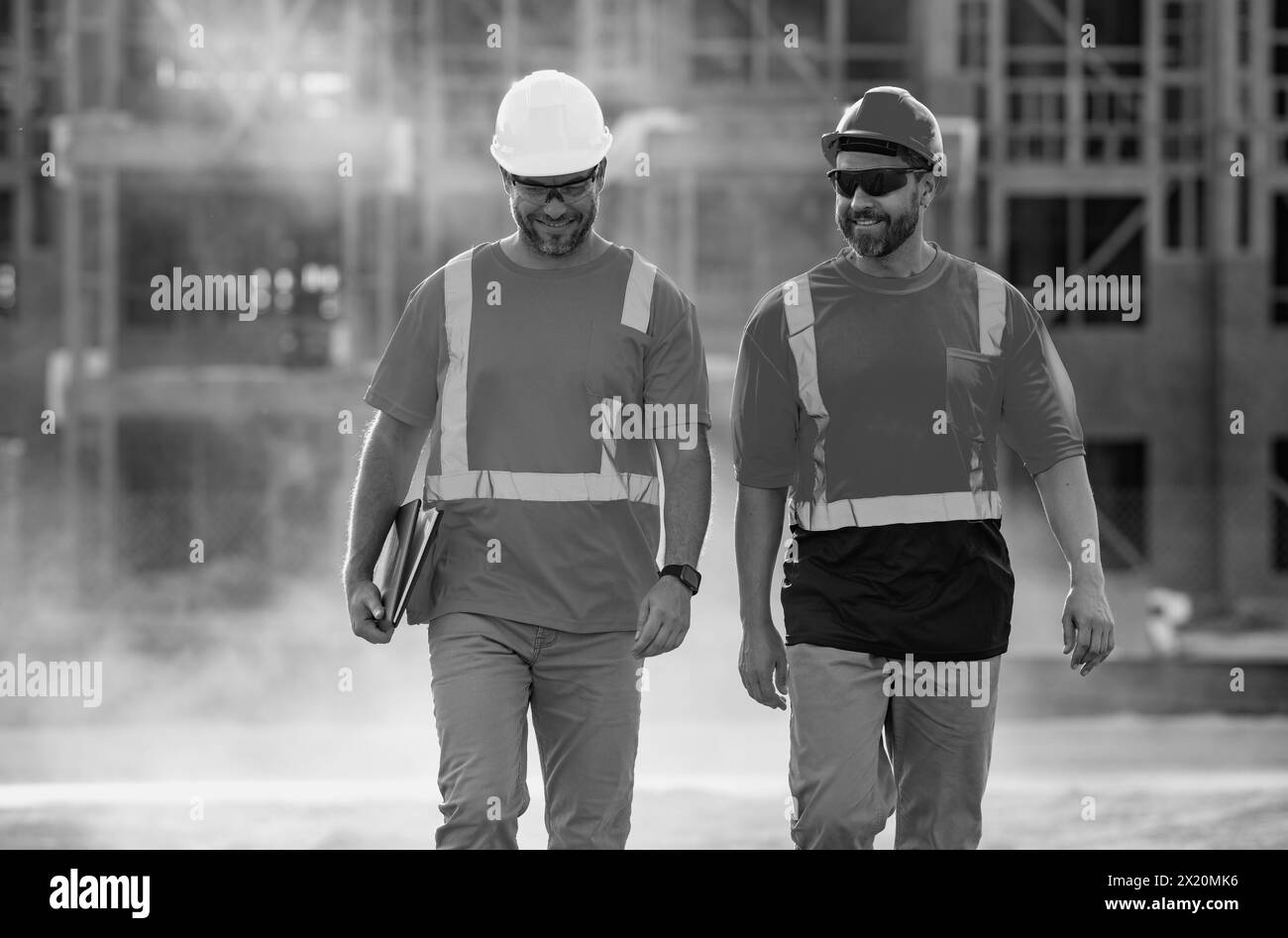 Two construction workers with hardhat helmet on construction site ...