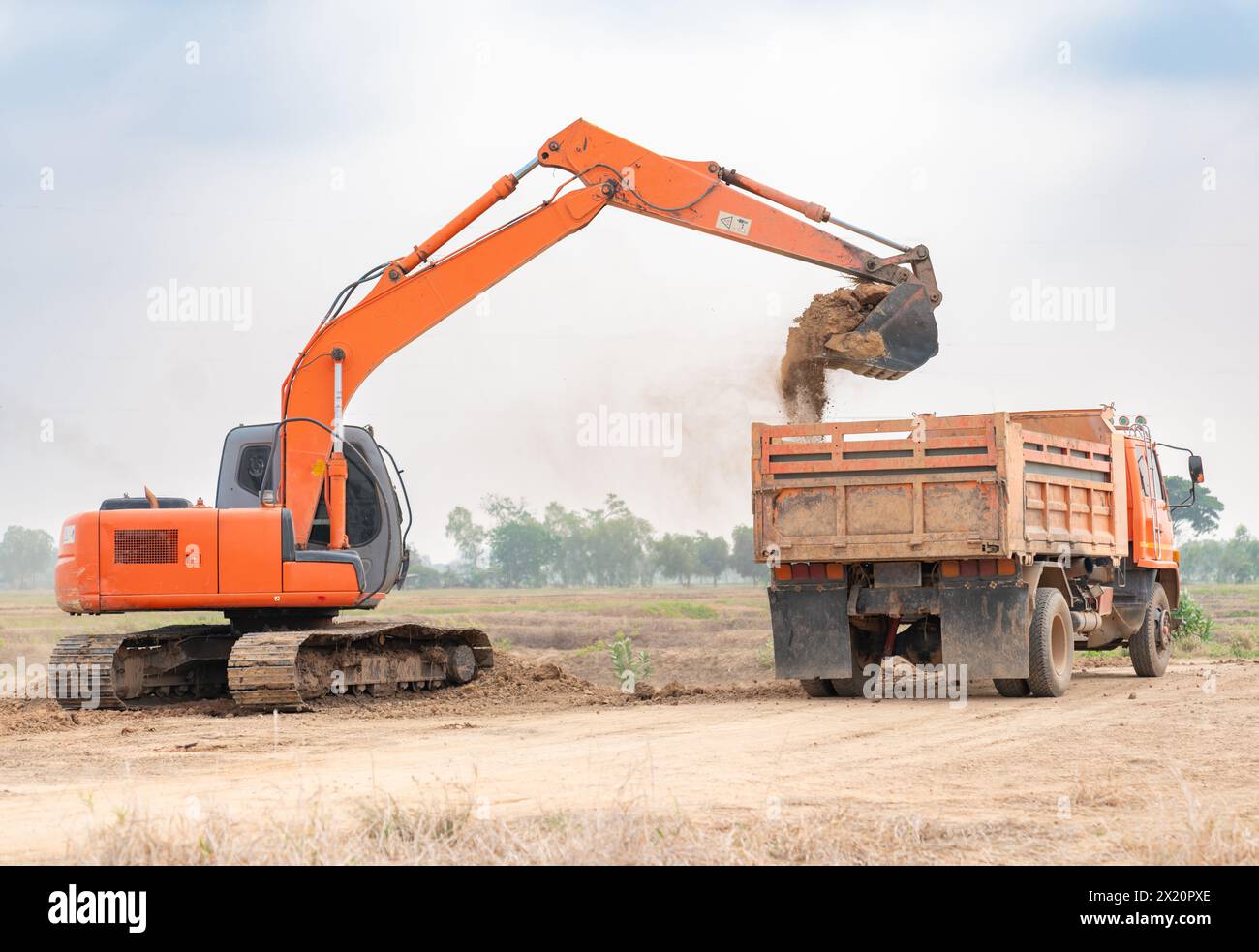Backhoes loading soil onto a dump truck at the rice field Stock Photo ...