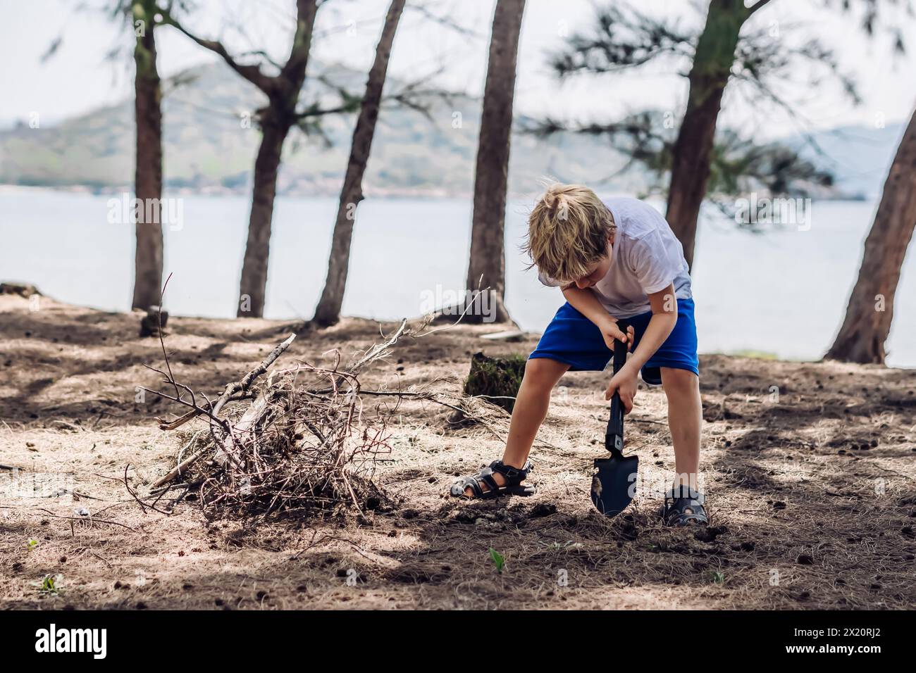 Cute boy digging soil in forest near sea beach. Family natural ...