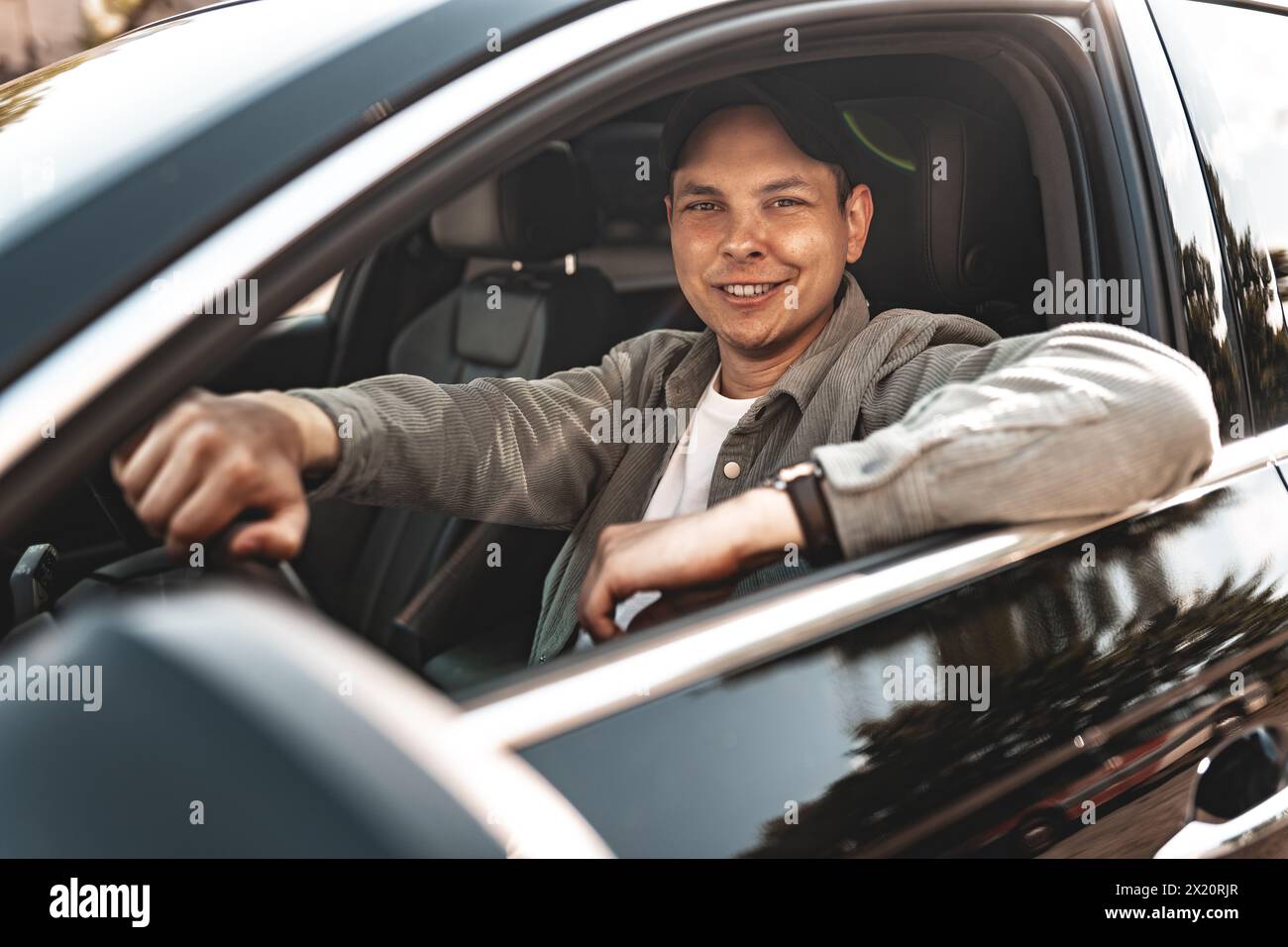 Young smiling man sitting in a car with open window Stock Photo - Alamy