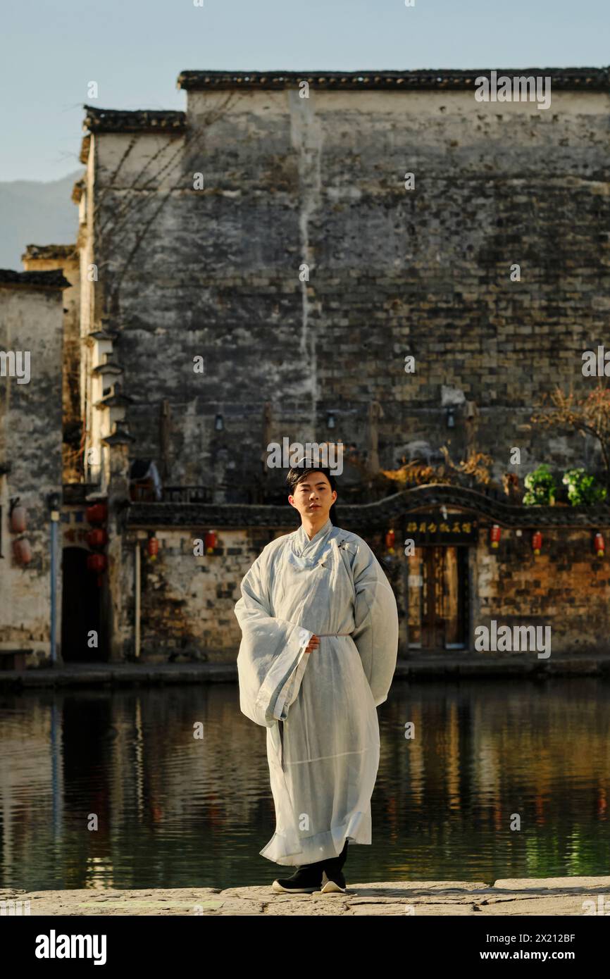 A man dressed in traditional hanfu costume poses for photos at Hongcun ...