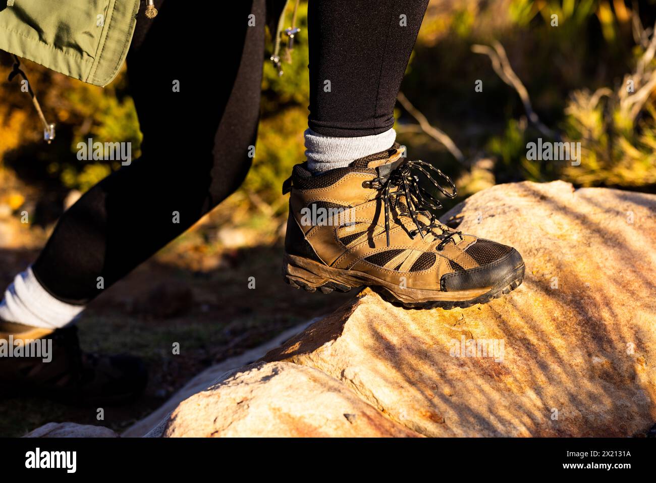 Biracial female hiker wearing hiking boots walking on rocks Stock Photo ...