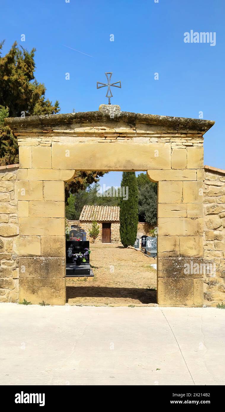 A stone archway with a cross on top. The archway is open and the sky is ...