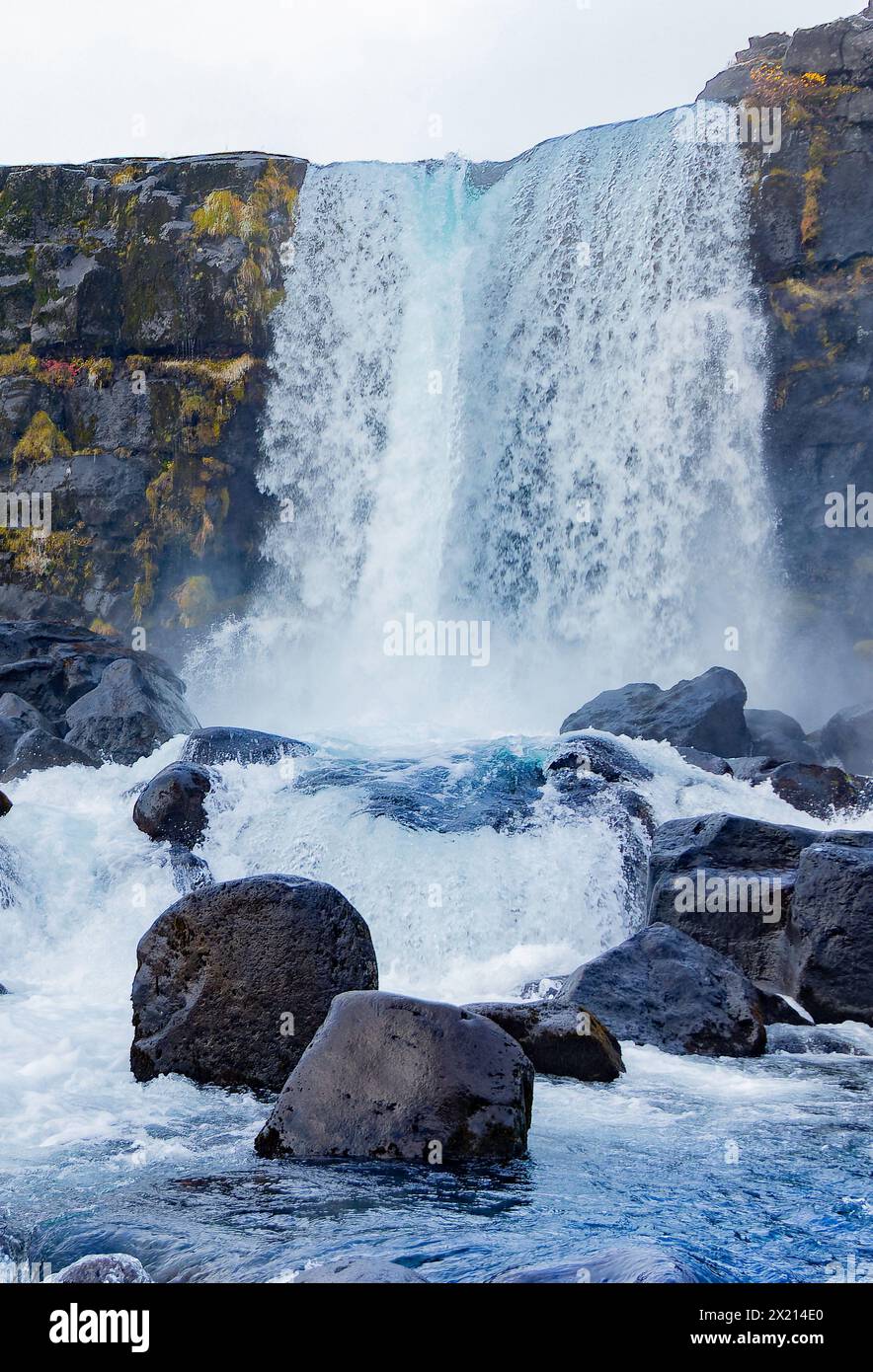 A waterfall with a large rock in front of it. The water is flowing down ...