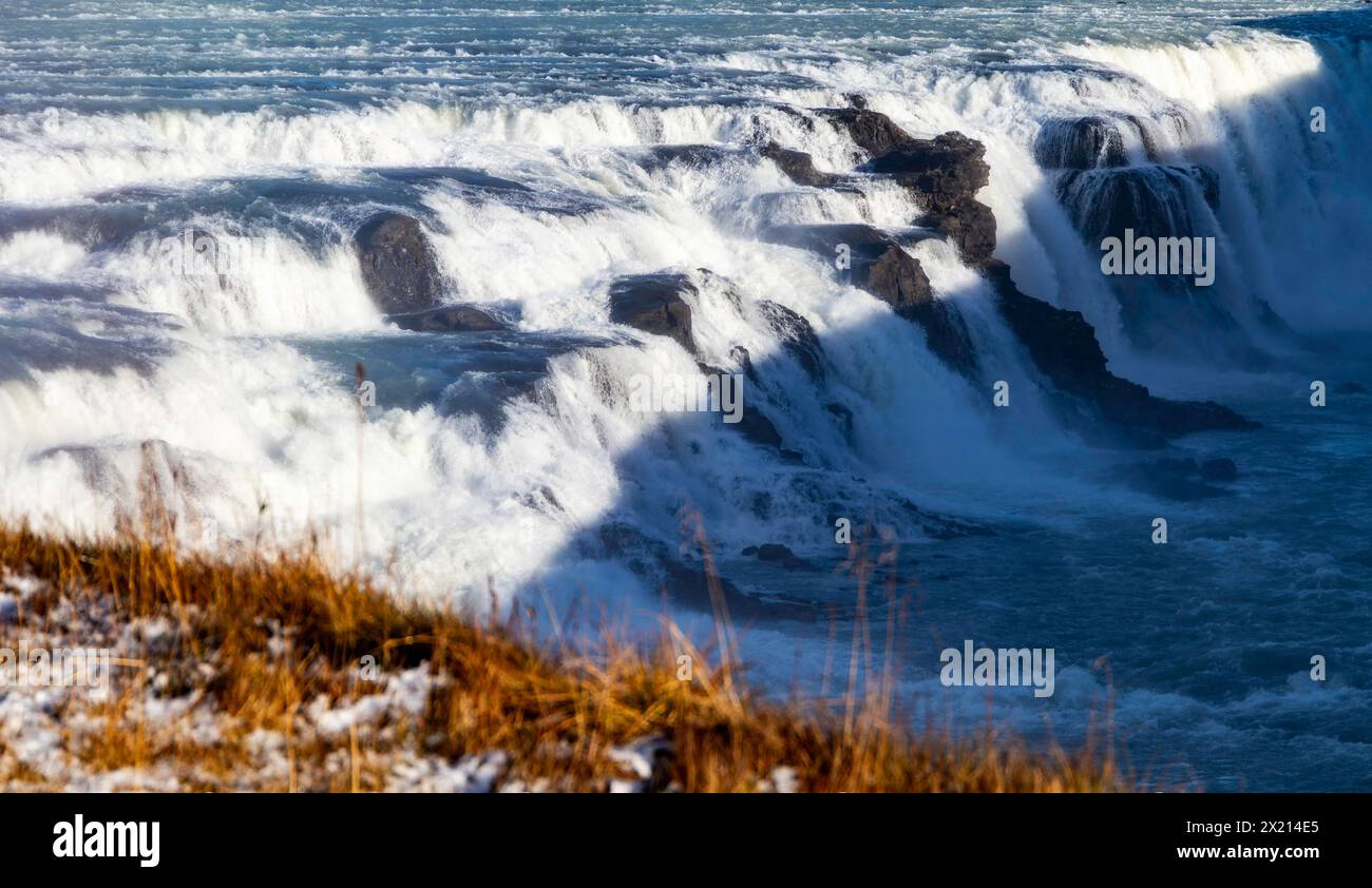 A waterfall with a rocky cliff behind it. The water is crashing down ...