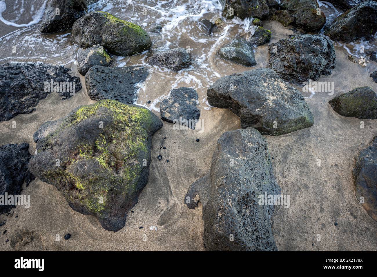 Large volcanic rocks embedded in the golden sands of Ka'anapali Beach ...