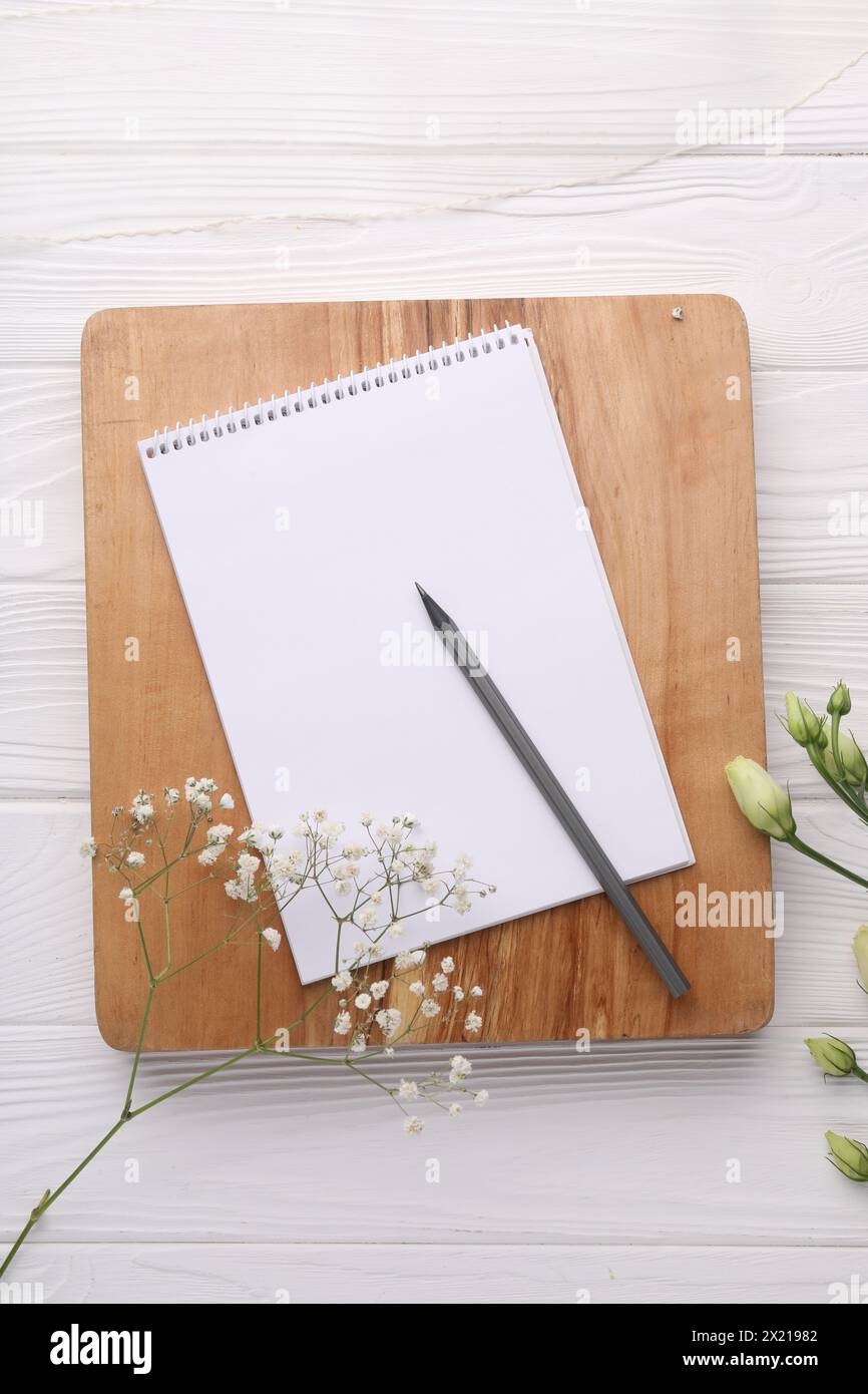 Guest list. Notebook, pencil and beautiful flowers on white wooden ...
