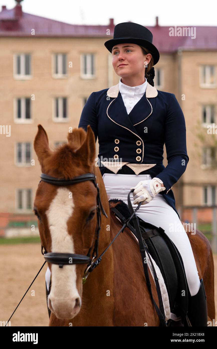 Dressage rider on chestnut horse with urban backdrop. Riding session ...