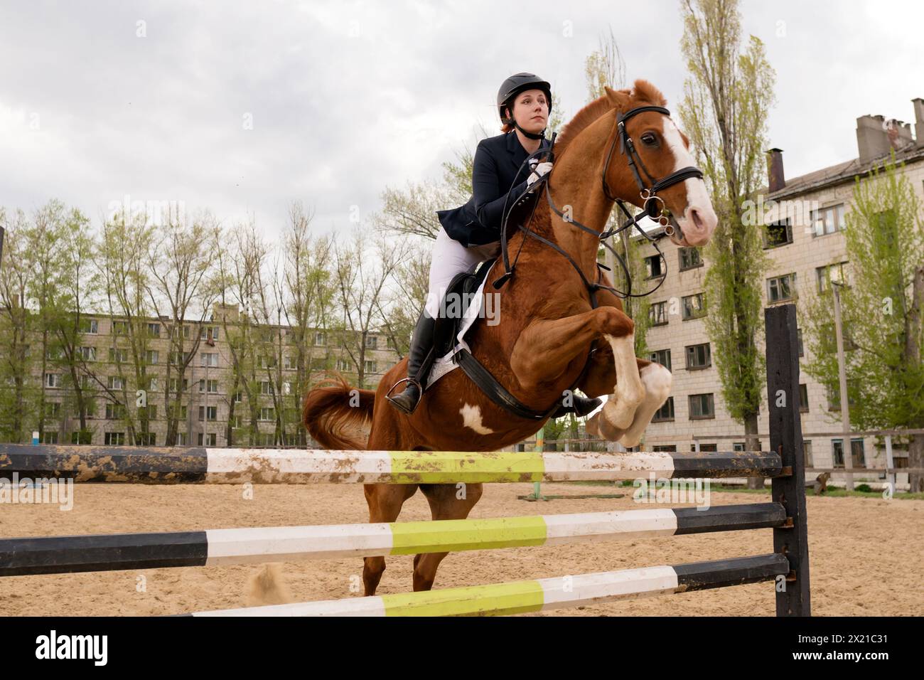 Front view of horse and rider executing jump. Female jockey in uniform ...