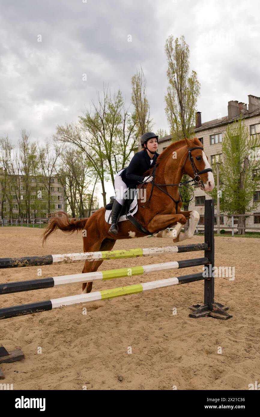 Focused rider clearing jump with horse, vertical shot. Female jockey in ...