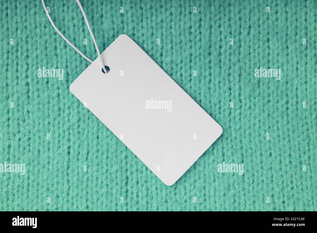 Blank clothing label on green knitted sweater background. Mockup ...