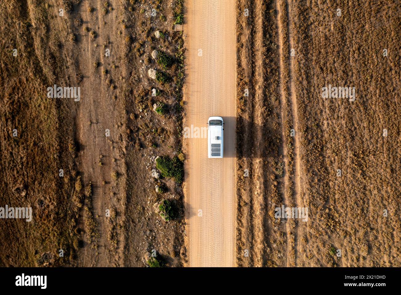 Camper van with solar panels on a dry landscape road drone top view ...