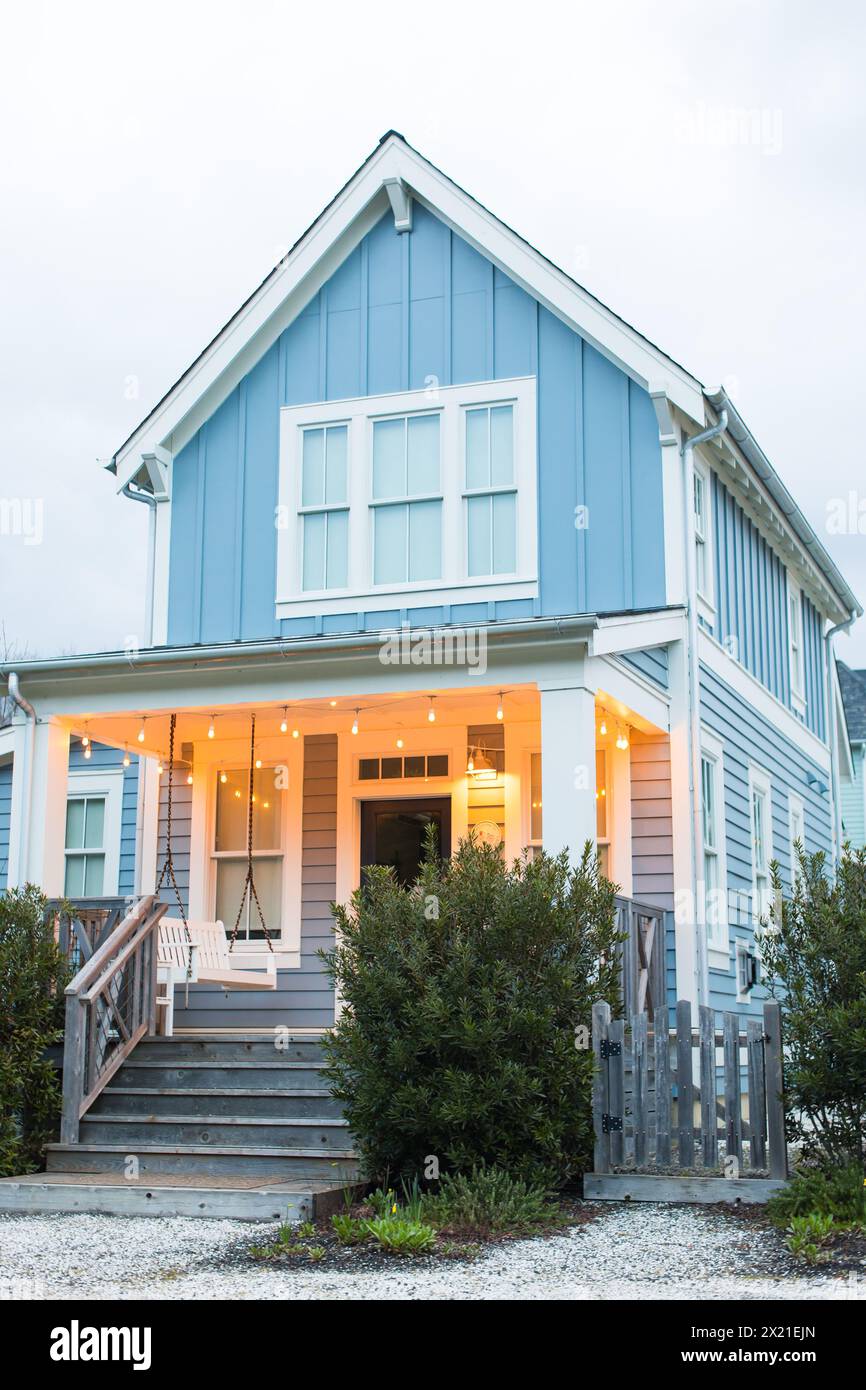 Evening view of blue house with cozy lit porch Stock Photo - Alamy