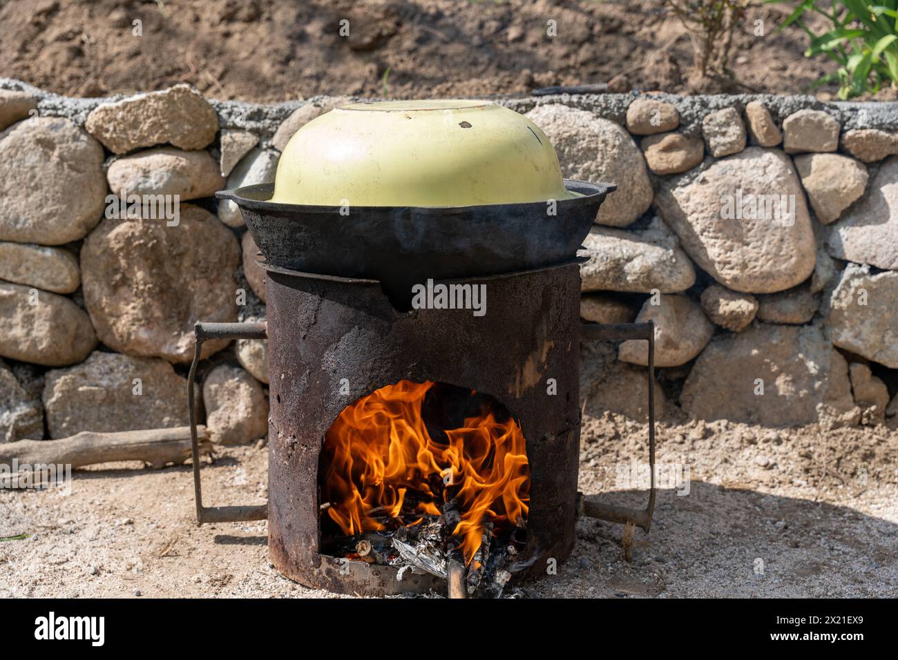 A rusty old pot is sitting on a fire in a pit Stock Photo - Alamy