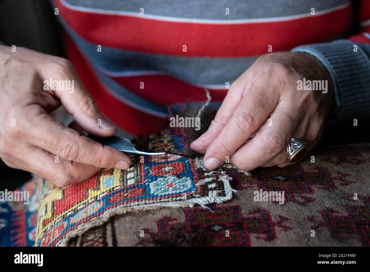 Detail of pulling thread restoration of antique carpet man's hands ...