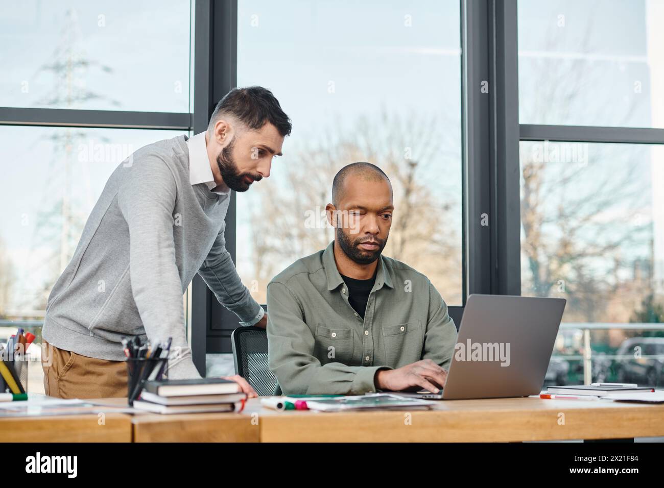Two men engaged in collaborative work on a laptop in a professional ...