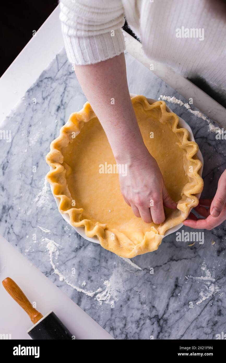 Preparing a fluted pie crust on a marble countertop Stock Photo - Alamy
