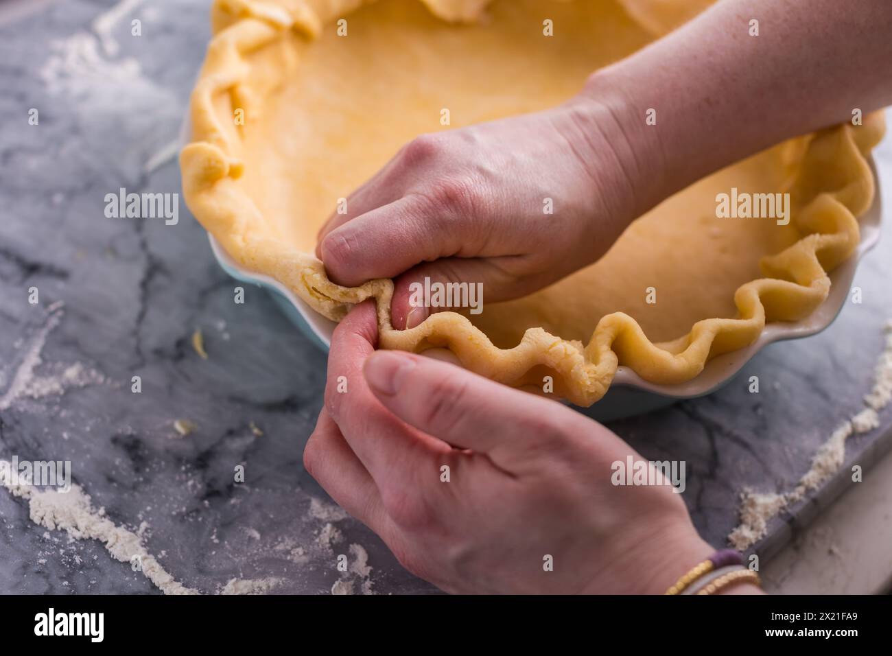Preparing a fluted pie crust on a marble countertop Stock Photo - Alamy