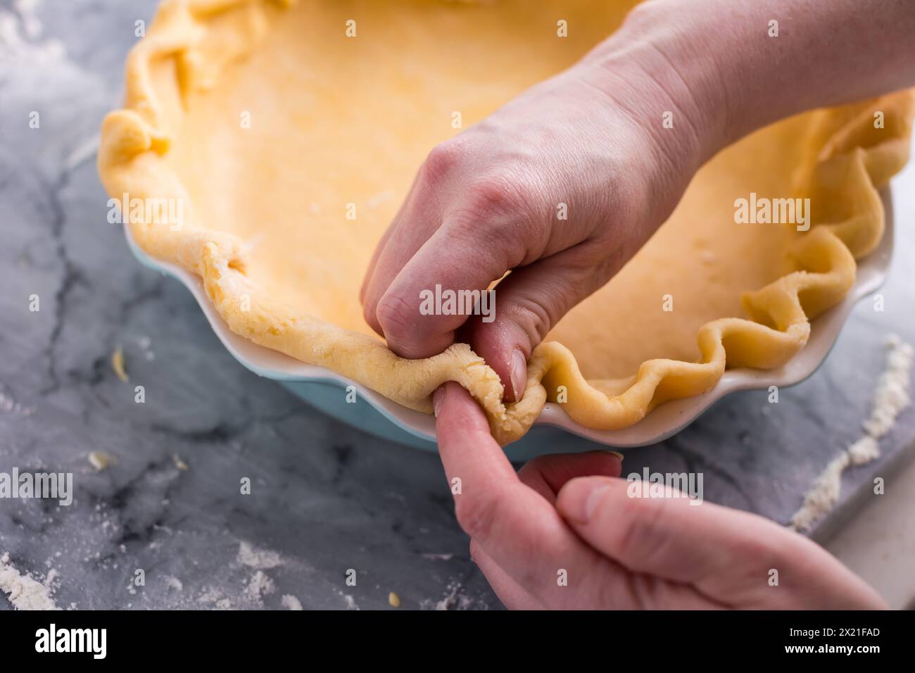 Preparing a fluted pie crust on a marble countertop Stock Photo - Alamy